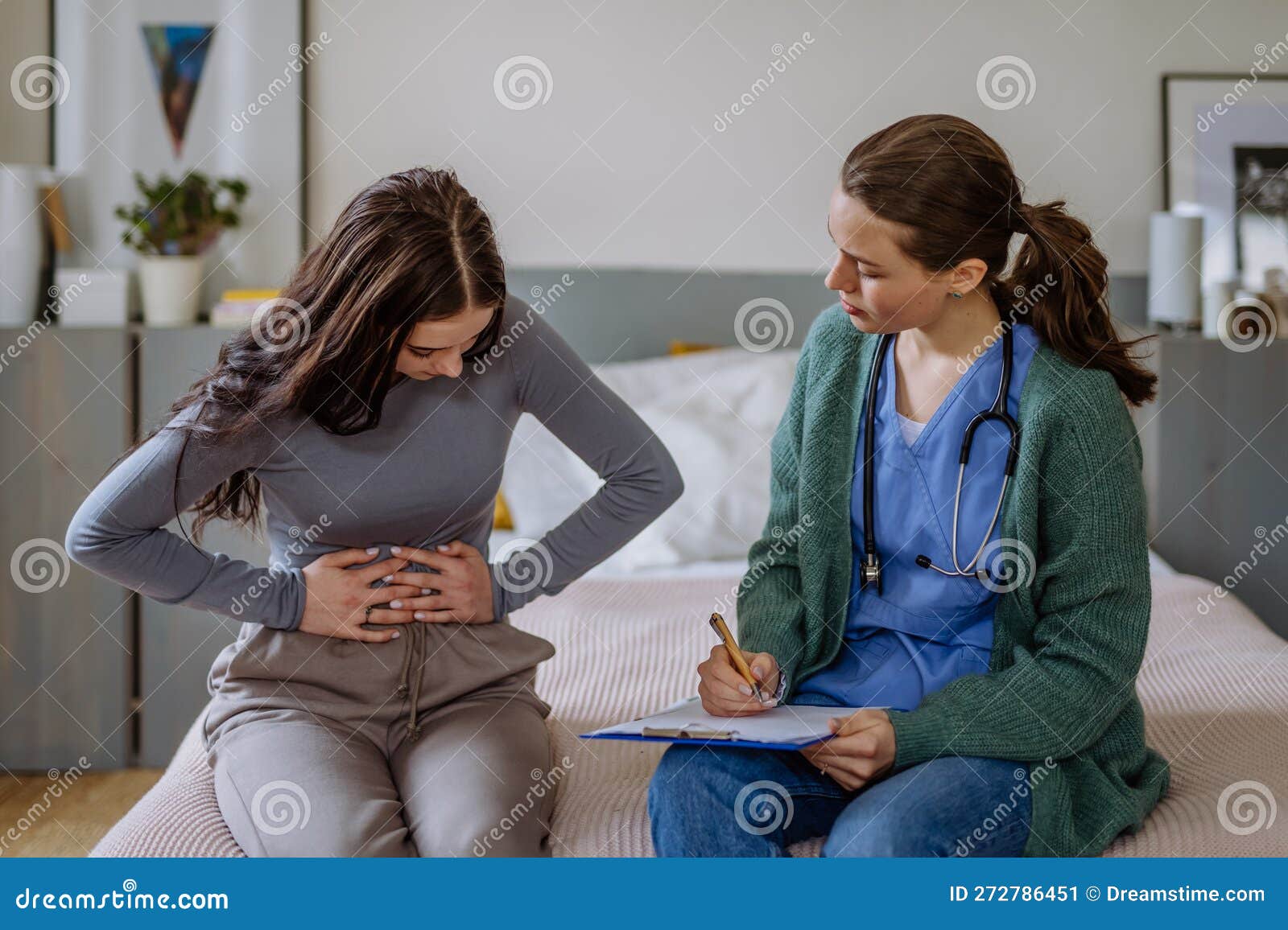 Teenage Girl Having Stomach Ache Young Doctor Examining Her Stock