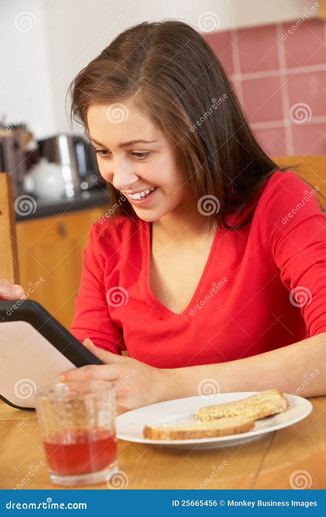 Teenage Girl Using Tablet Computer Whilst Eating Stock Photo - Image of ...