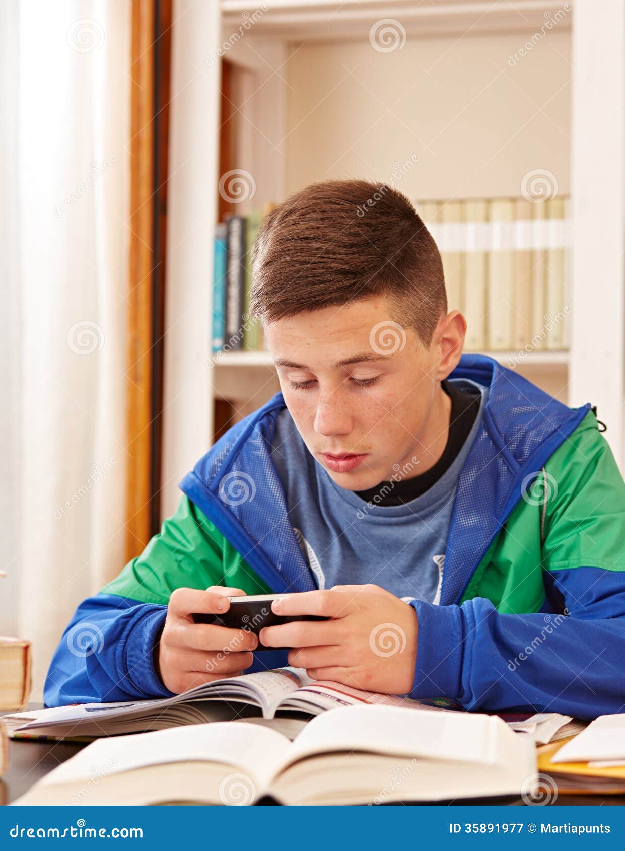 Teenager Texting with Smartphone while Studying Stock Image - Image of ...