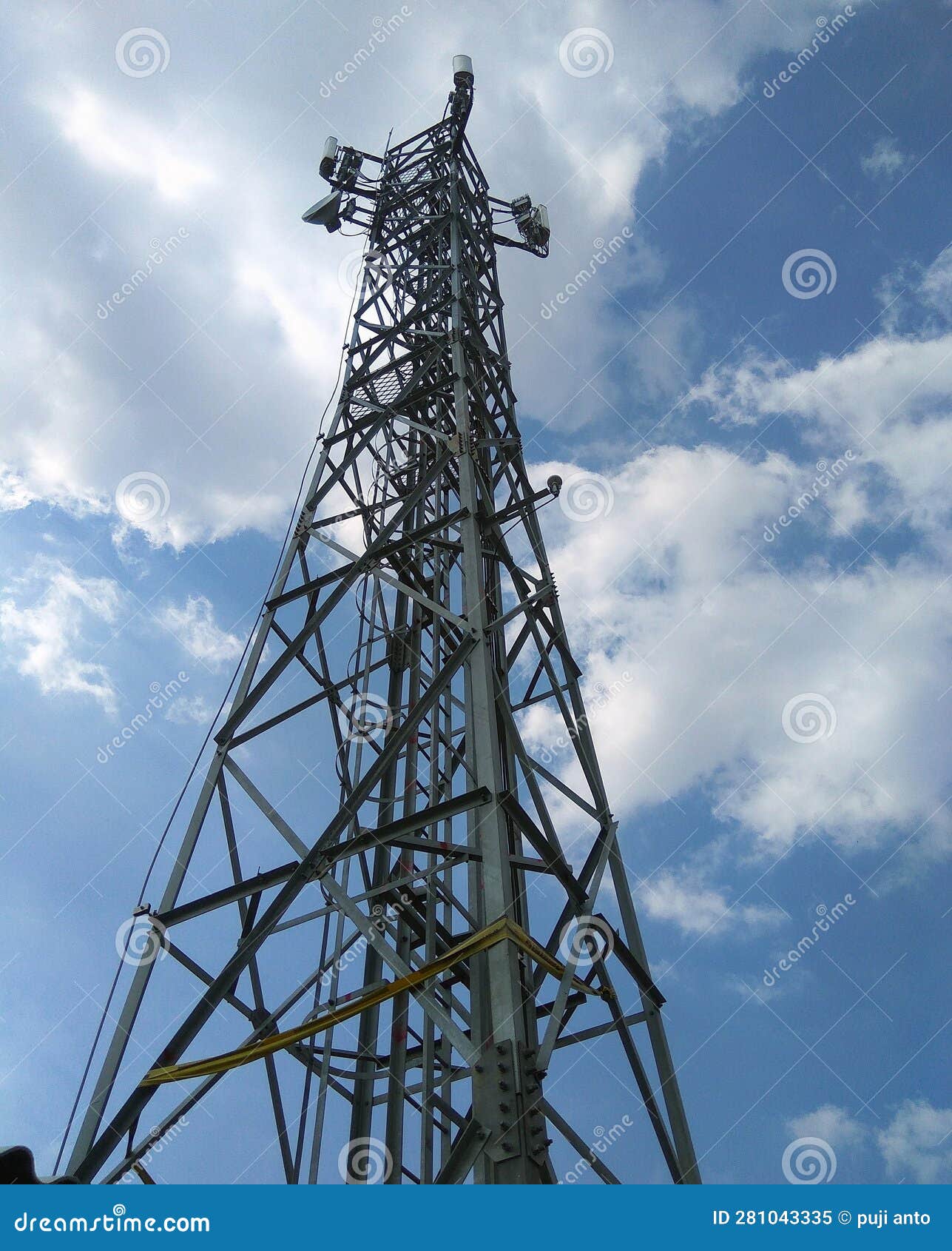 A Telecommunication Tower with a Tall Building, Against a Bright Cloudy ...