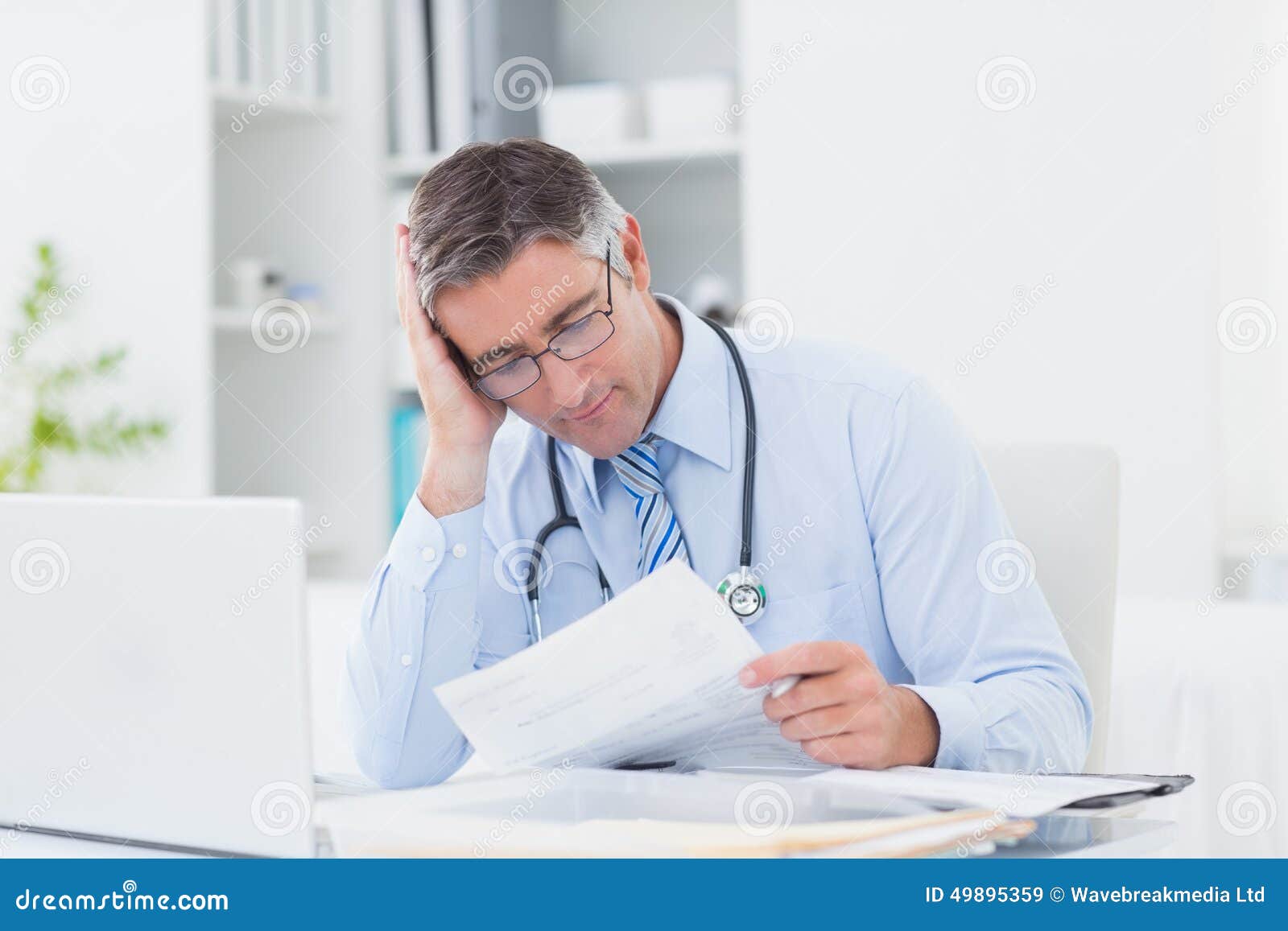 Tensed Male Doctor Reading Document in Clinic Stock Image - Image of ...