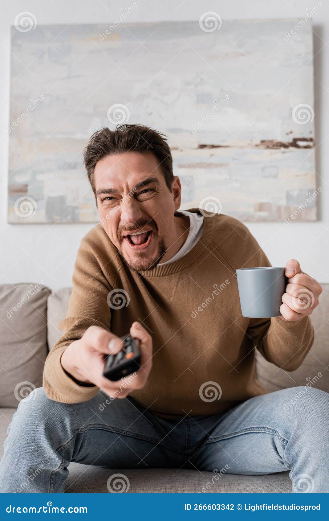 Tensed Man Holding Remote Controller and Stock Photo - Image of jumper ...