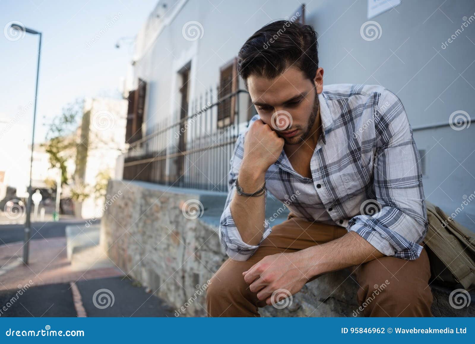 Tensed Man Looking Down while Sitting on Retaining Wall Stock Photo ...