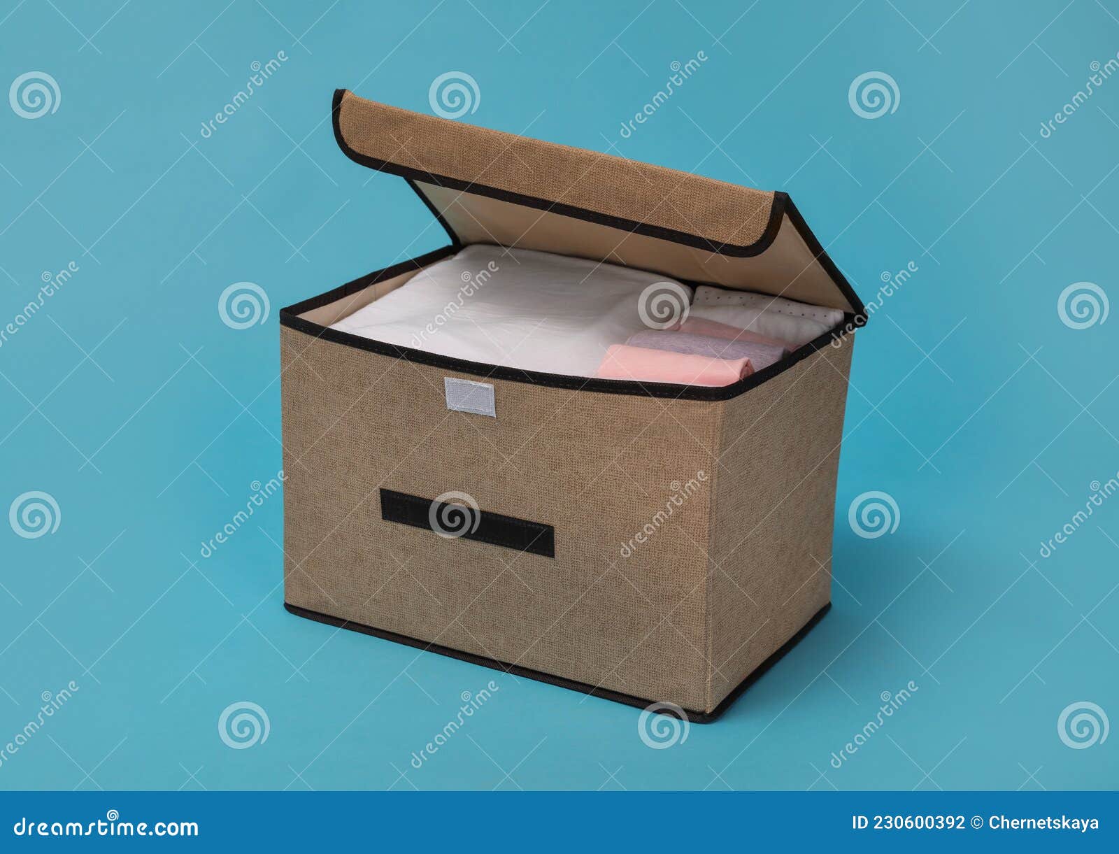 Textile Storage Case with Folded Clothes on Light Blue Background Stock ...
