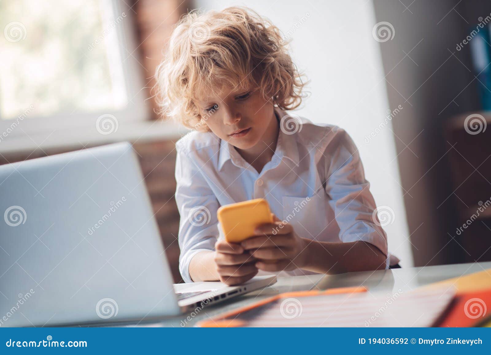Cute Blonde Boy Holding His Smartphone and Texting Stock Photo - Image ...