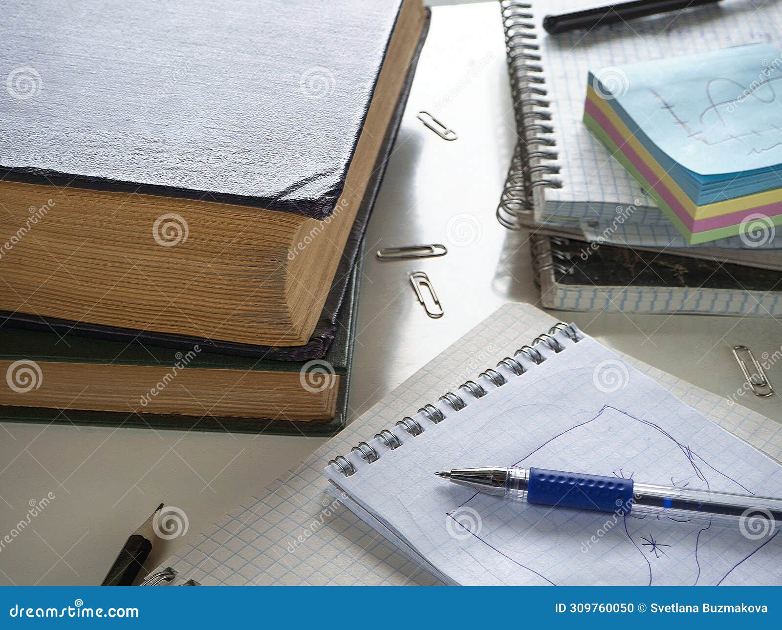 There are Books, Notebooks, a Notepad with a Pen on the Table. There is ...