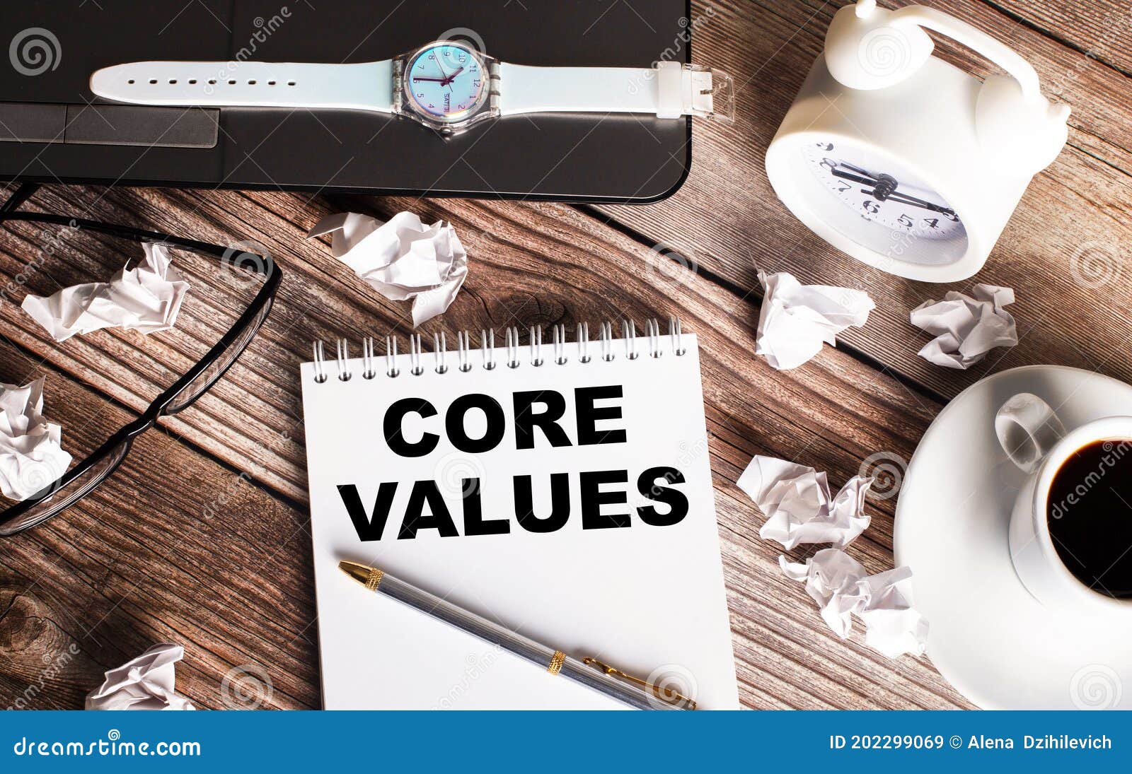 There is a Cup of Coffee on a Wooden Table, a Clock, Glasses and a ...