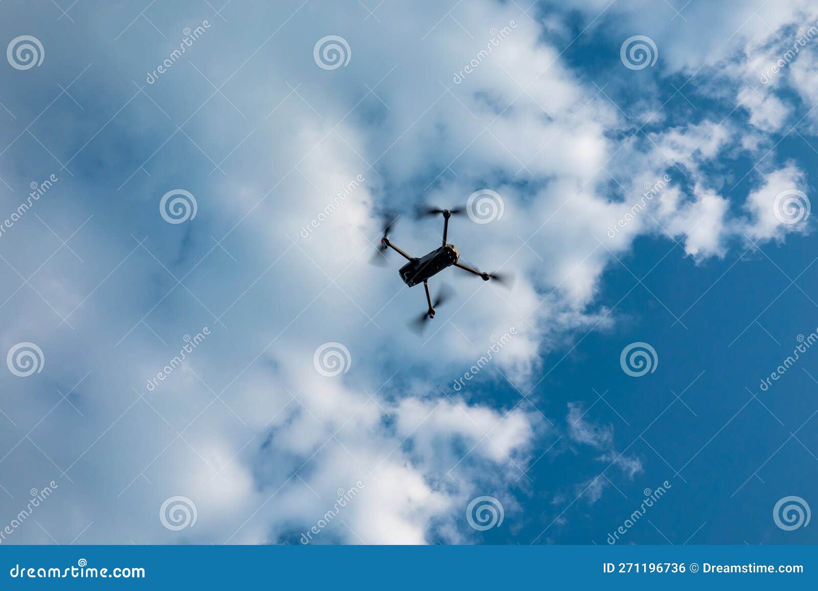 A DJI Drone Flying Under White Clouds and Blue Sky Stock Photo - Image ...