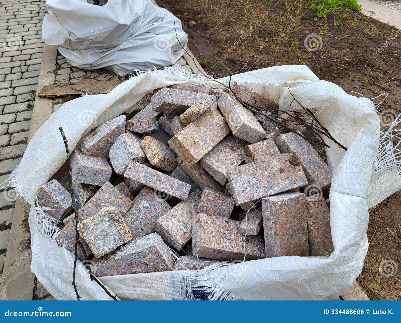 There is a White Garbage Bag with Fragments of Bricks on the Sidewalk ...