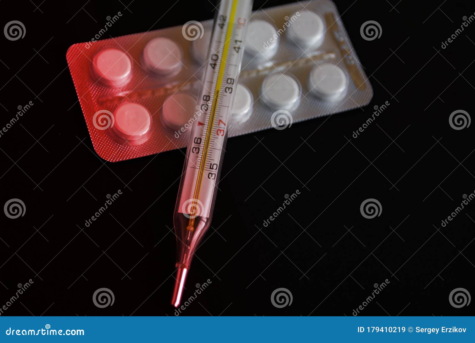 A Thermometer with a High Temperature and Pack of Medications on a Dark ...