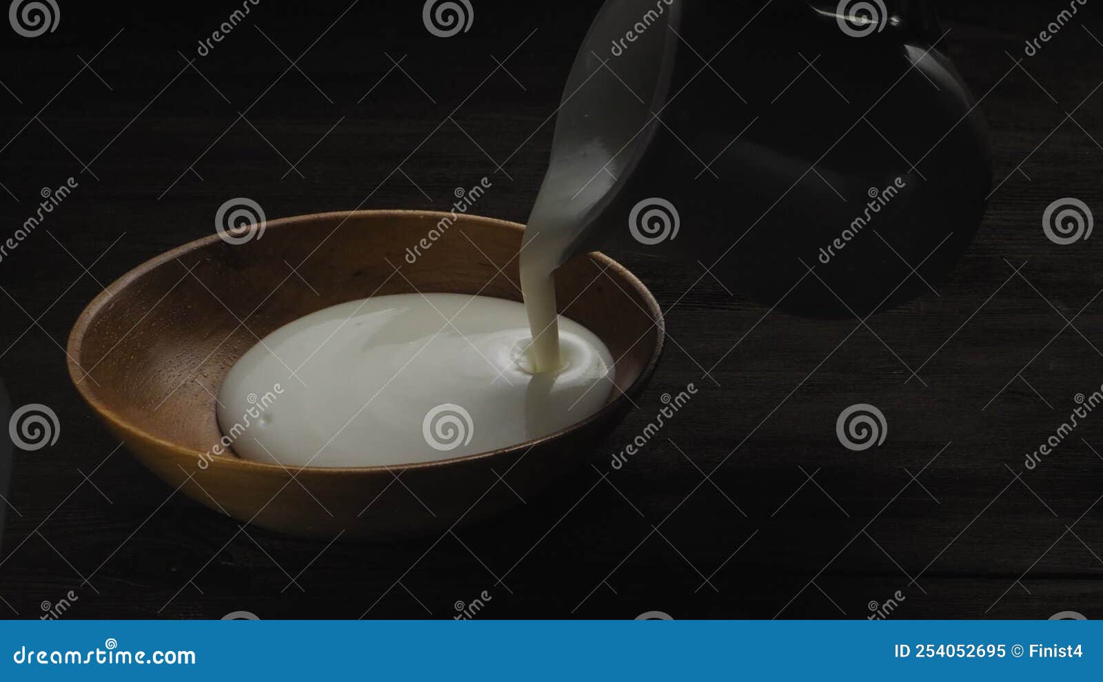 Thick Cream is Poured from a Jug into a Wooden Plate on a Black ...