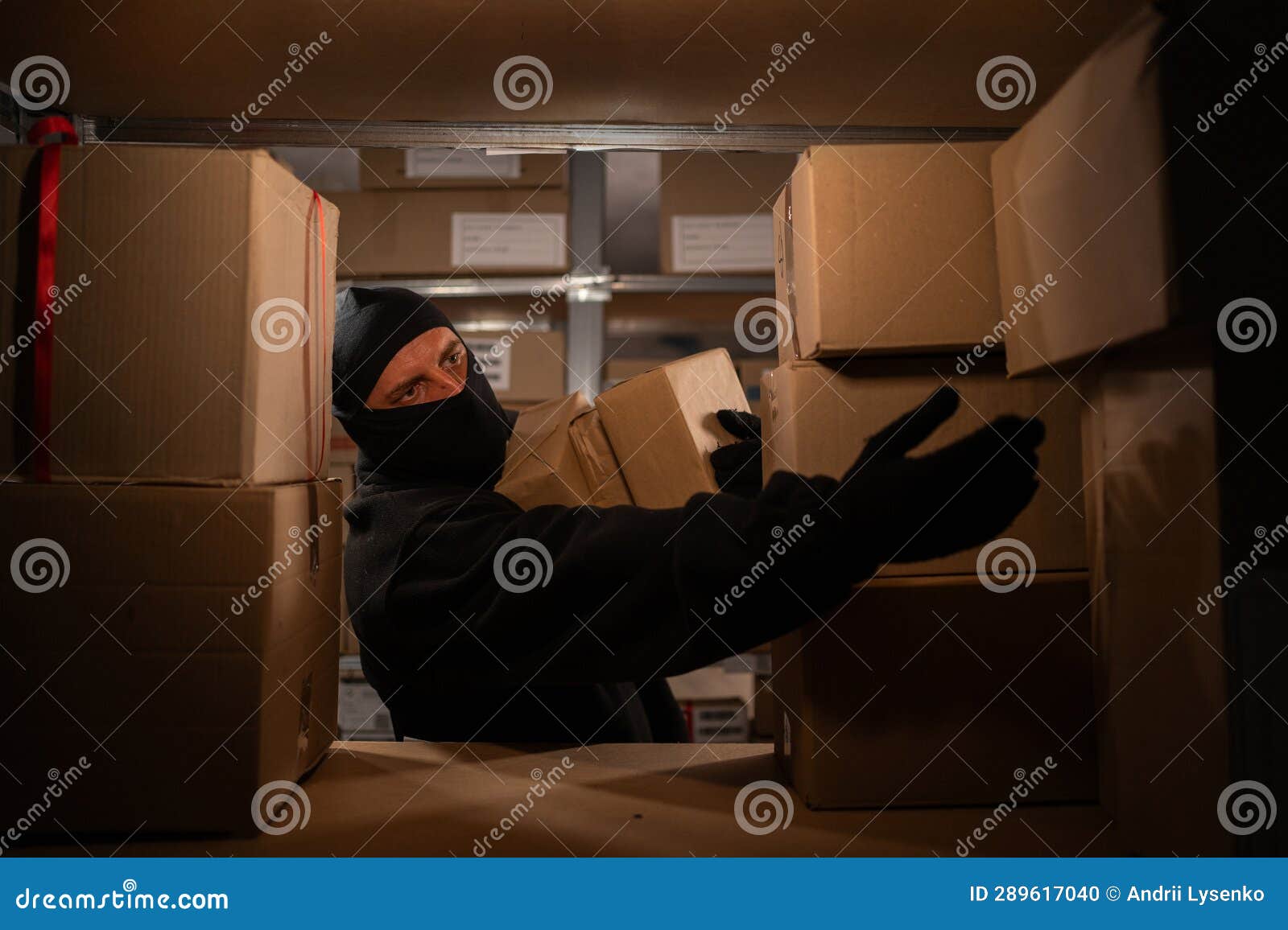 Thief in Black Balaclava Steals with a Parcel in a Warehouse at the ...