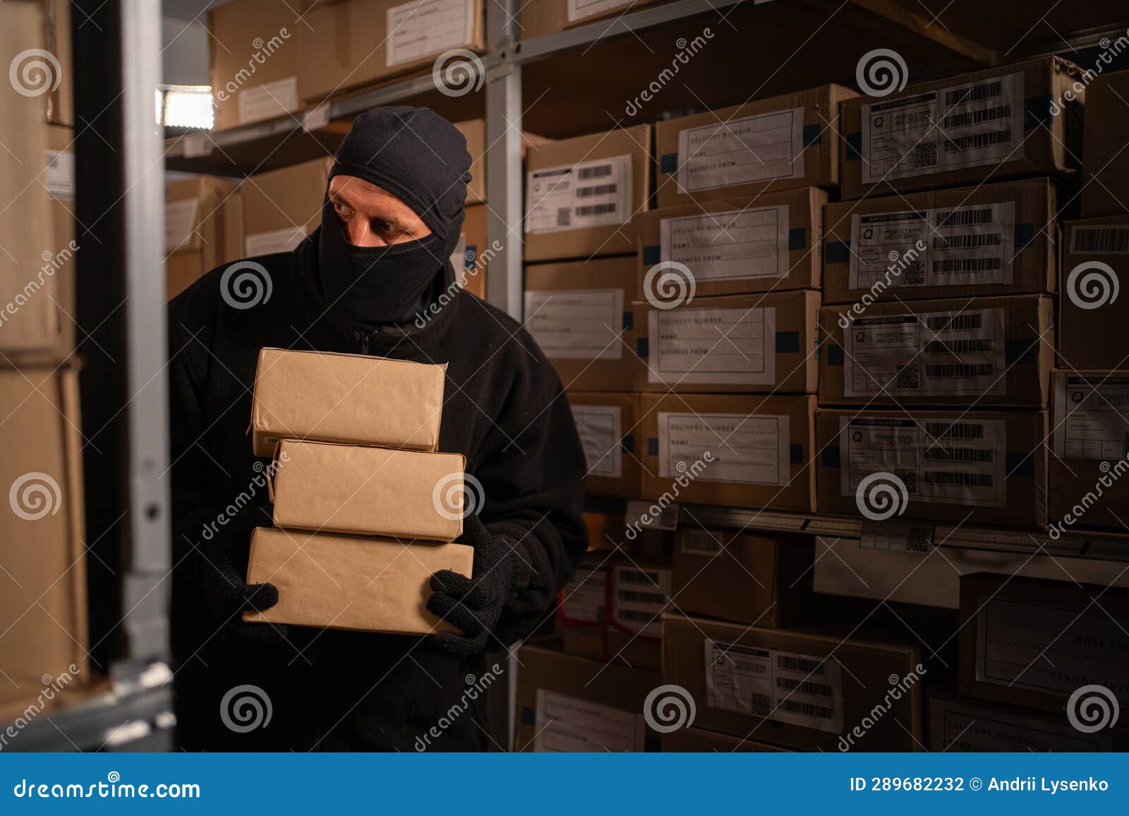 Thief in Black Balaclava Steals with a Parcel in a Warehouse at the ...