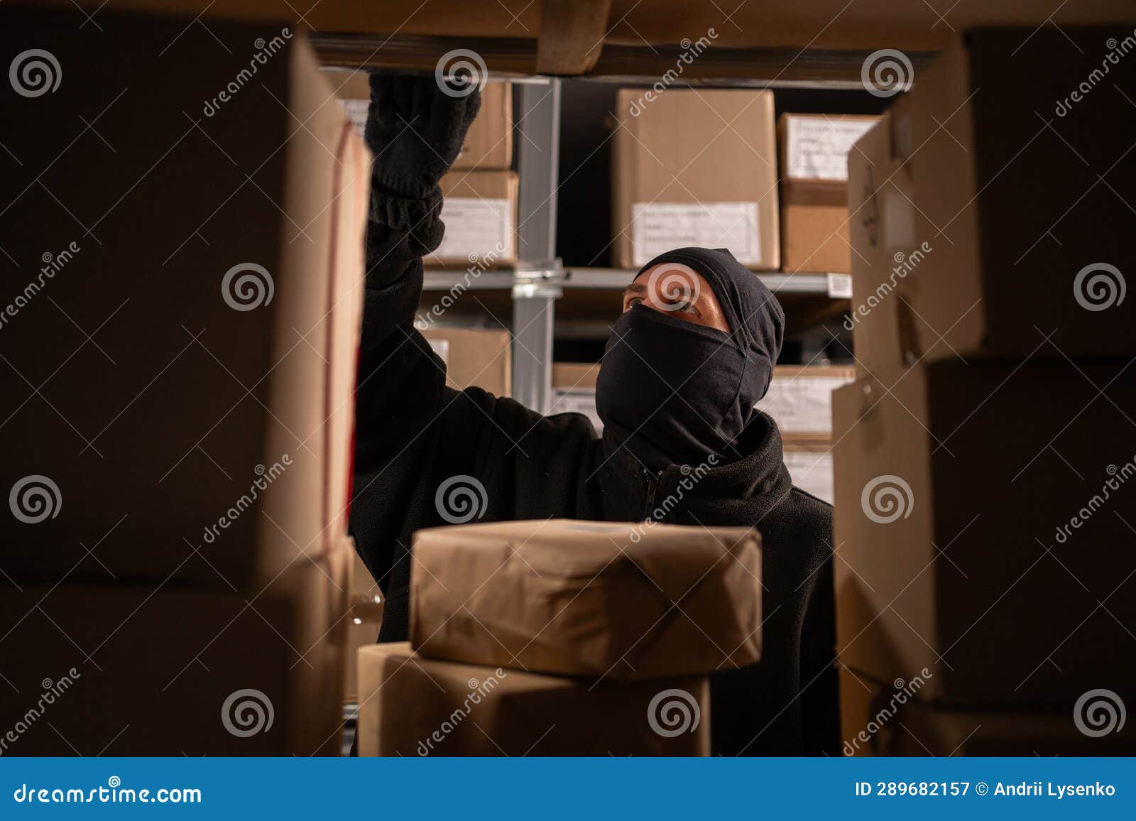 Thief in a Black Mask Steals a Box of Parcel in a Warehouse, Close-up ...