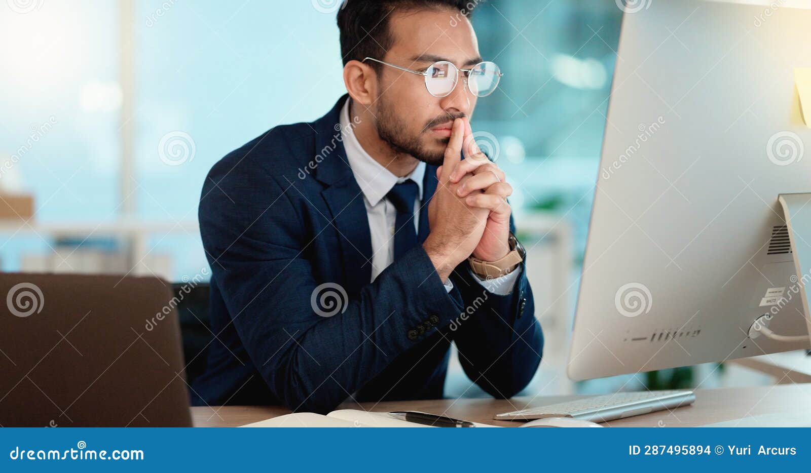 Thinking it Manager Working on a Desktop Computer and Laptop in a ...