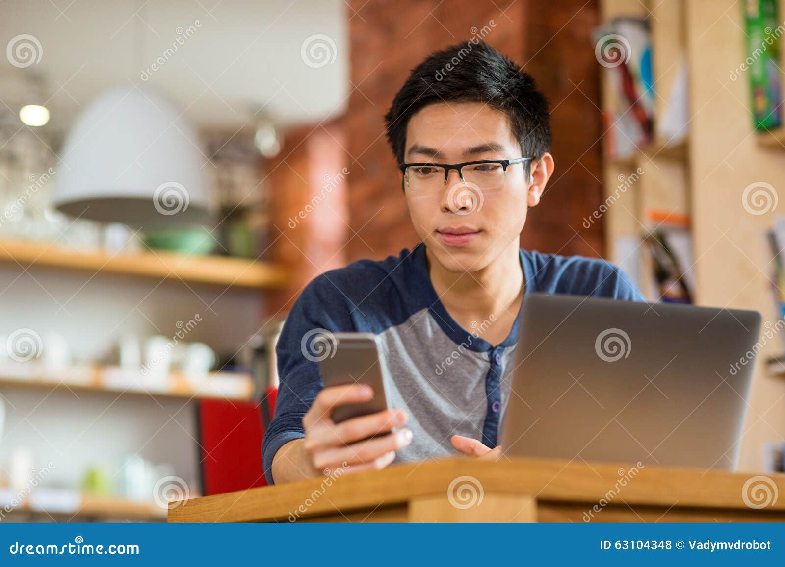 Thoughtful Asian Man Using Smartphone and Laptop Stock Photo - Image of ...