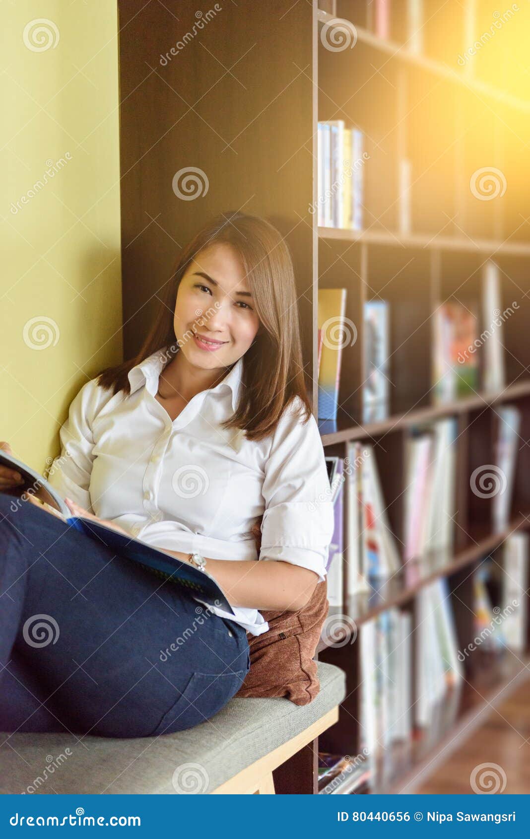 Thoughtful Female Student Sitting Against Bookshelf Stock Photo - Image ...