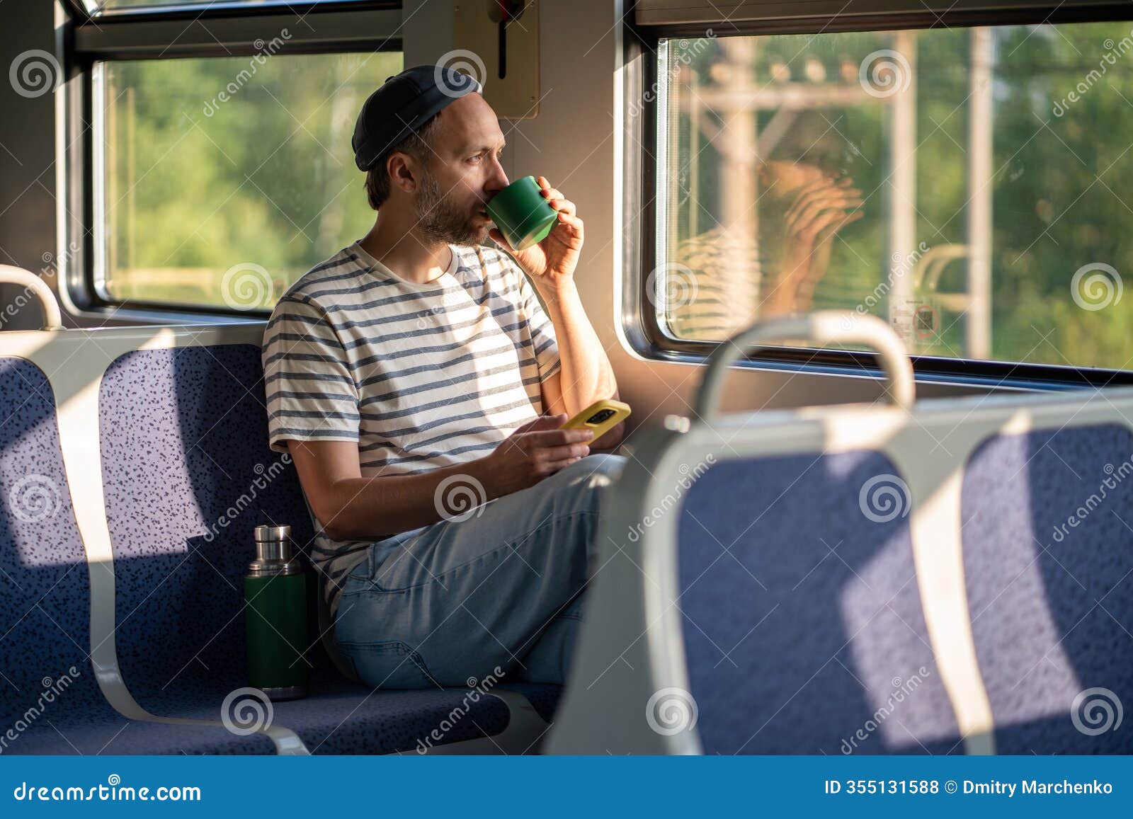 Thoughtful Man Sips Tea from Thermos Mug while Looking Out the Window ...