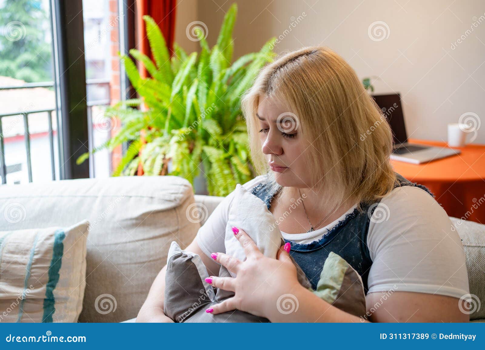 Thoughtful Plus-size Woman Sitting on a Couch Holding a Pillow Stock ...