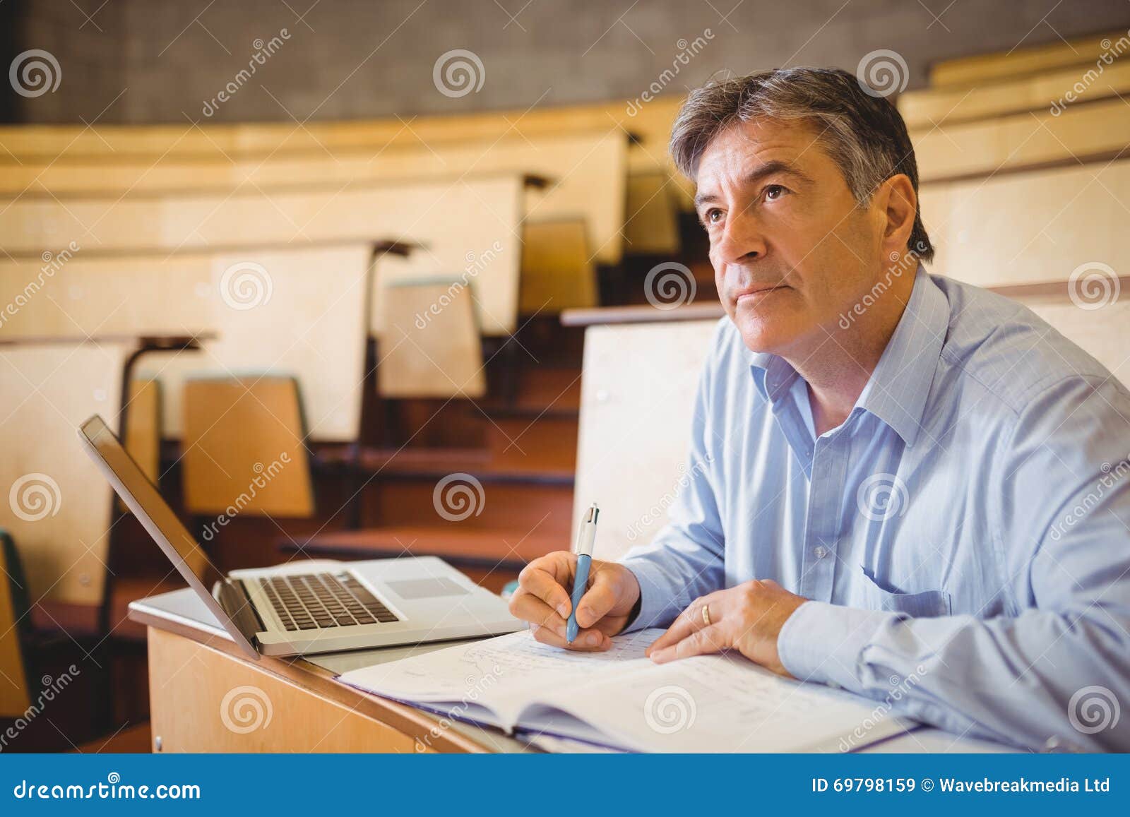 Thoughtful Professor Writing in Book at Desk Stock Image - Image of ...