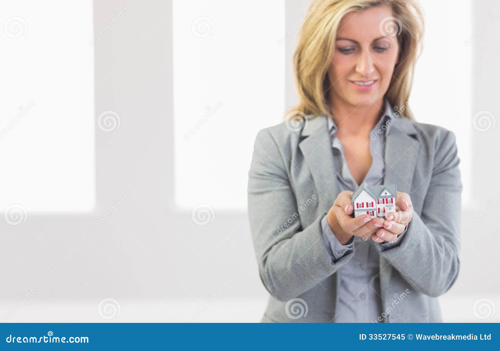 Thoughtful Realtor Standing Looking and Presenting a Mini Model Stock ...