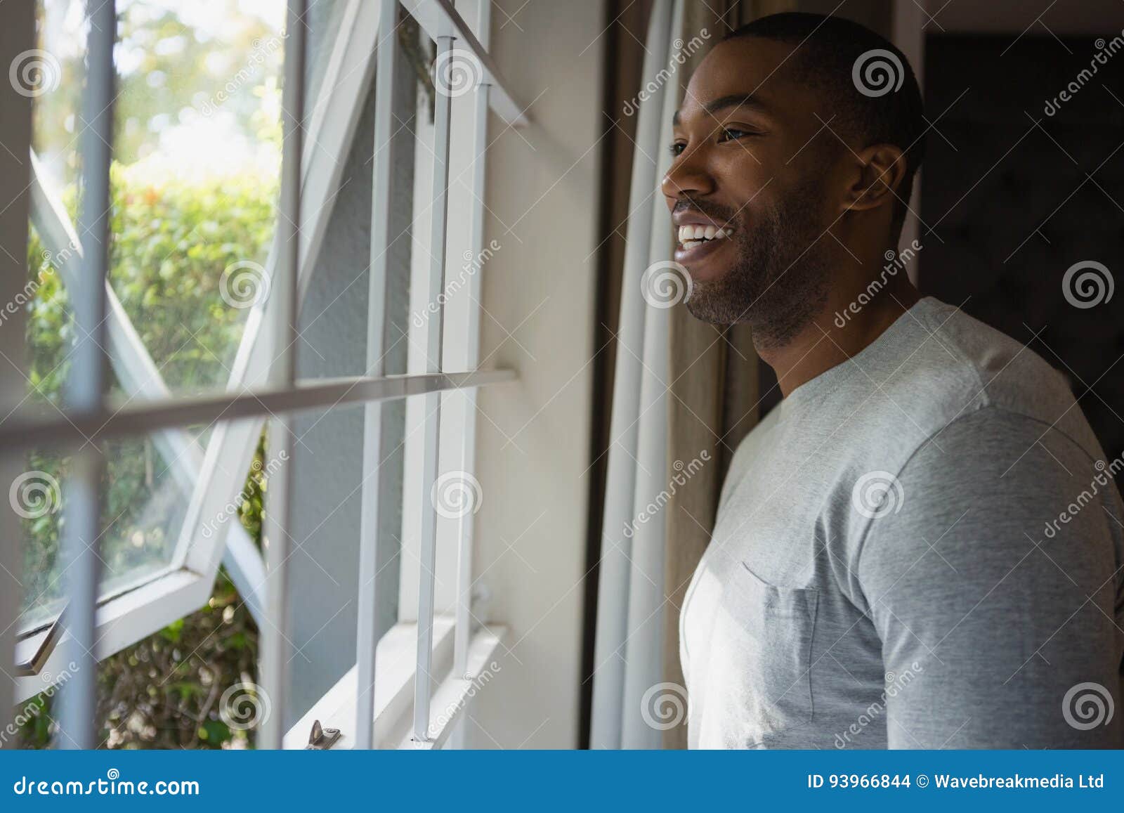 Thoughtful Smiling Man Looking Out through Window at Home Stock Photo ...