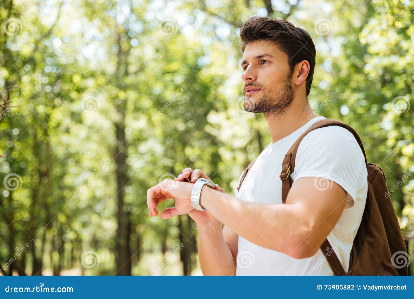 Thoughtful Young Man with Backpack Looking at Watch in Forest Stock ...