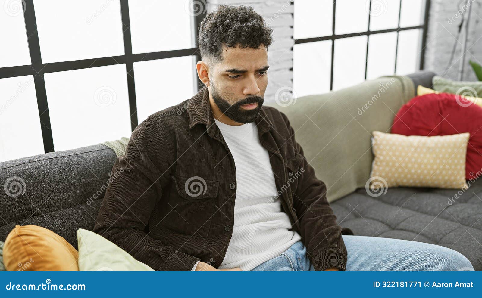 Thoughtful Young Man with Beard Sitting on Couch at Home Looking ...
