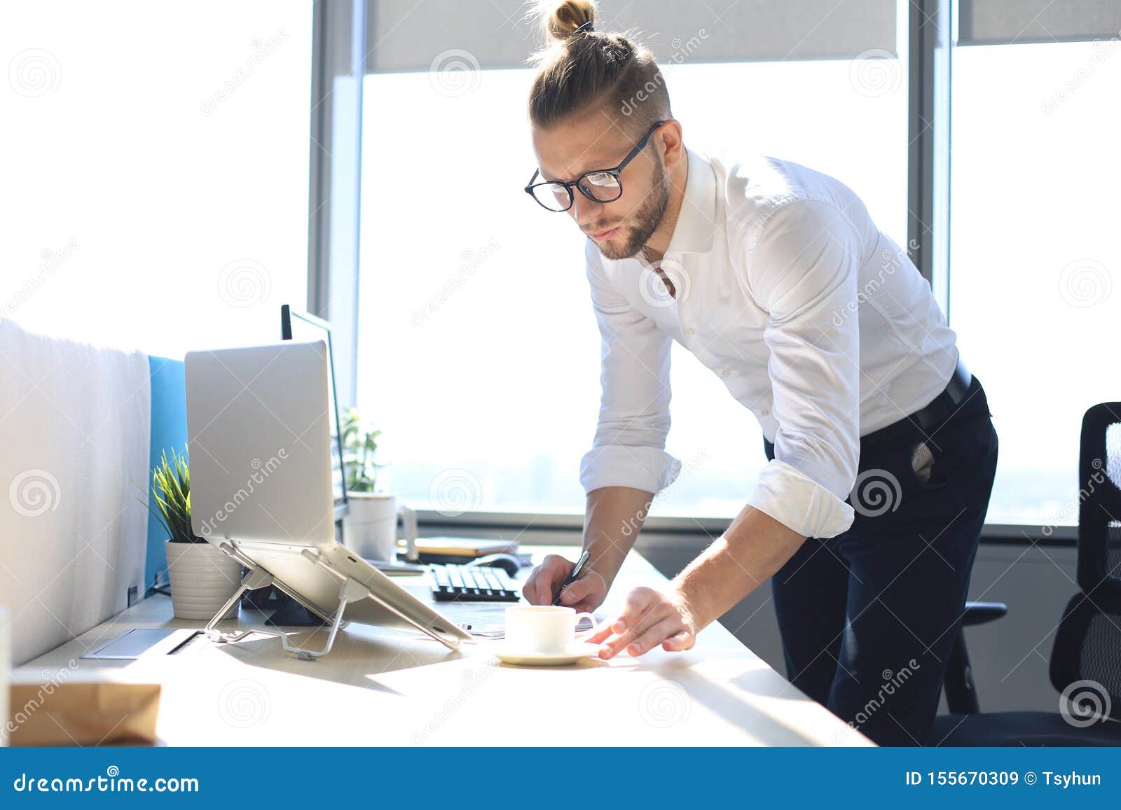 Thoughtful Young Man Writing Something Down while Working in the ...