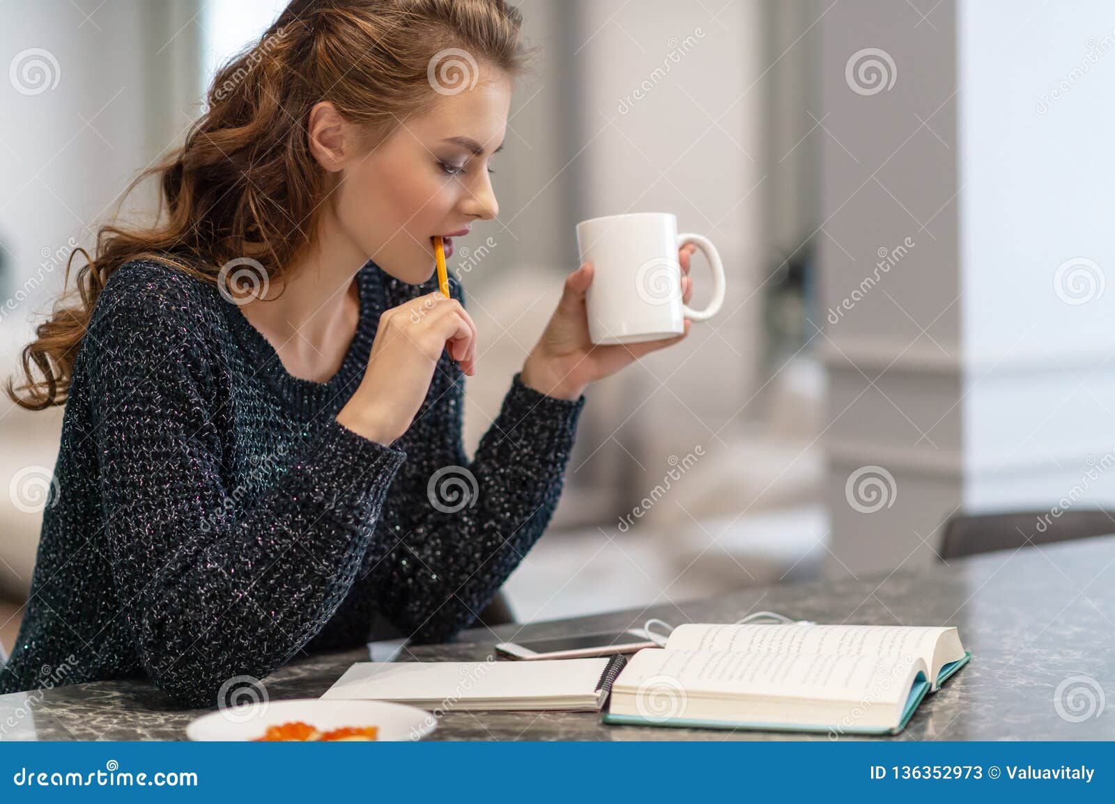 Thoughtful Young Woman Making Notes Using Notepad in Kitchen Stock ...
