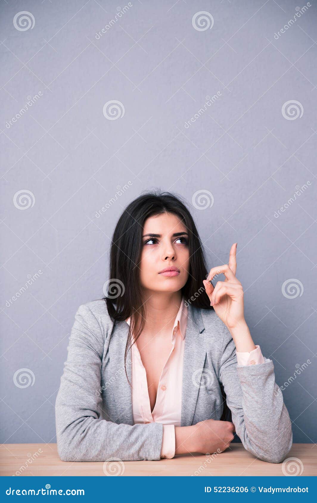 Thoughtful Young Woman Sitting at the Table and Pointing Up Stock Photo ...