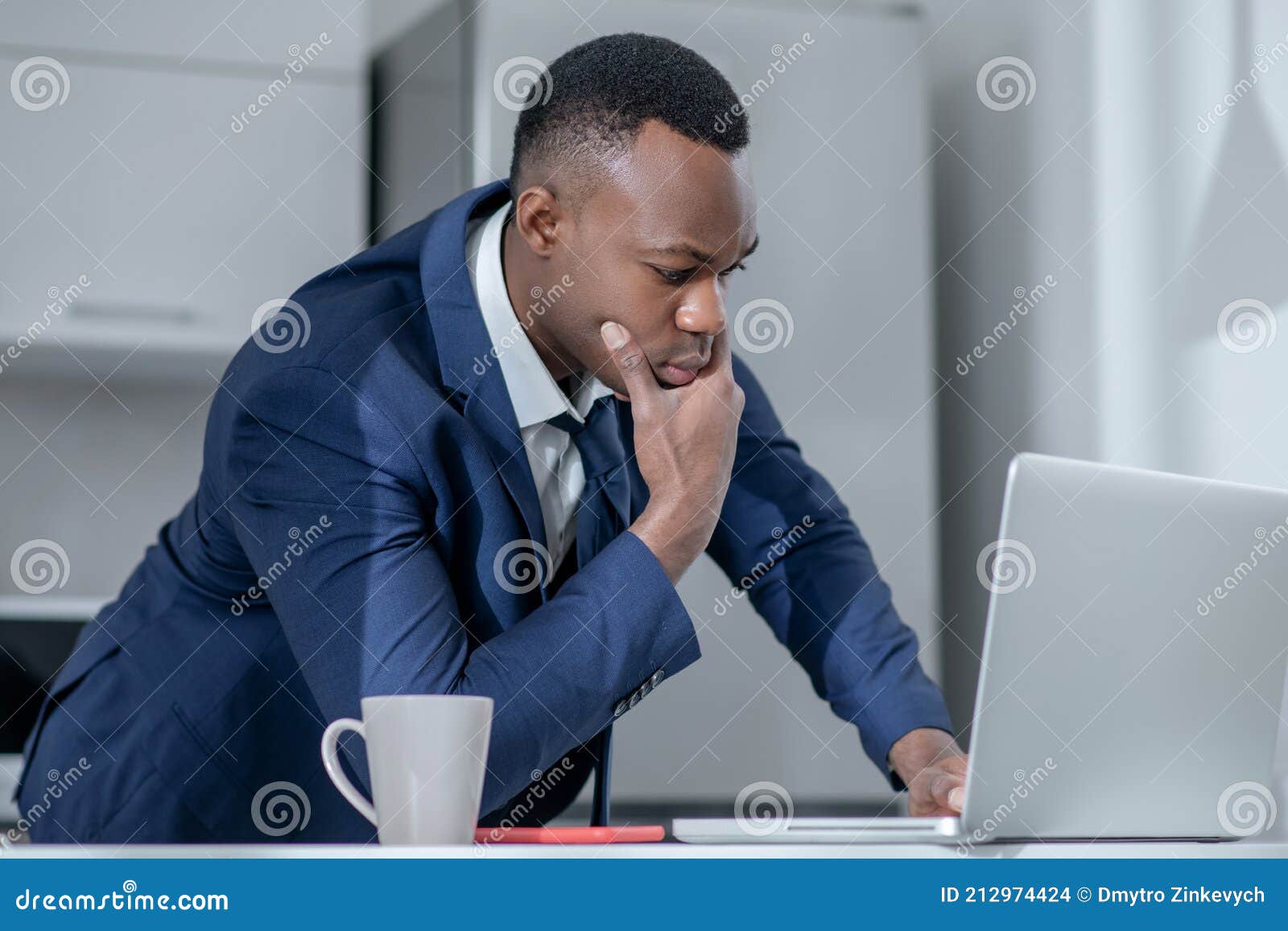 Elegant Dark-skinned Man Reading Something on Laptop and Looking ...