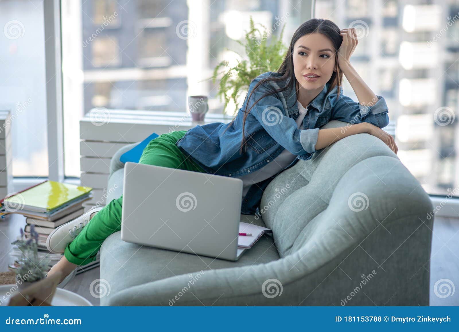 Young Woman in a Jeans Jacket Sitting on the Sofa and Looking ...