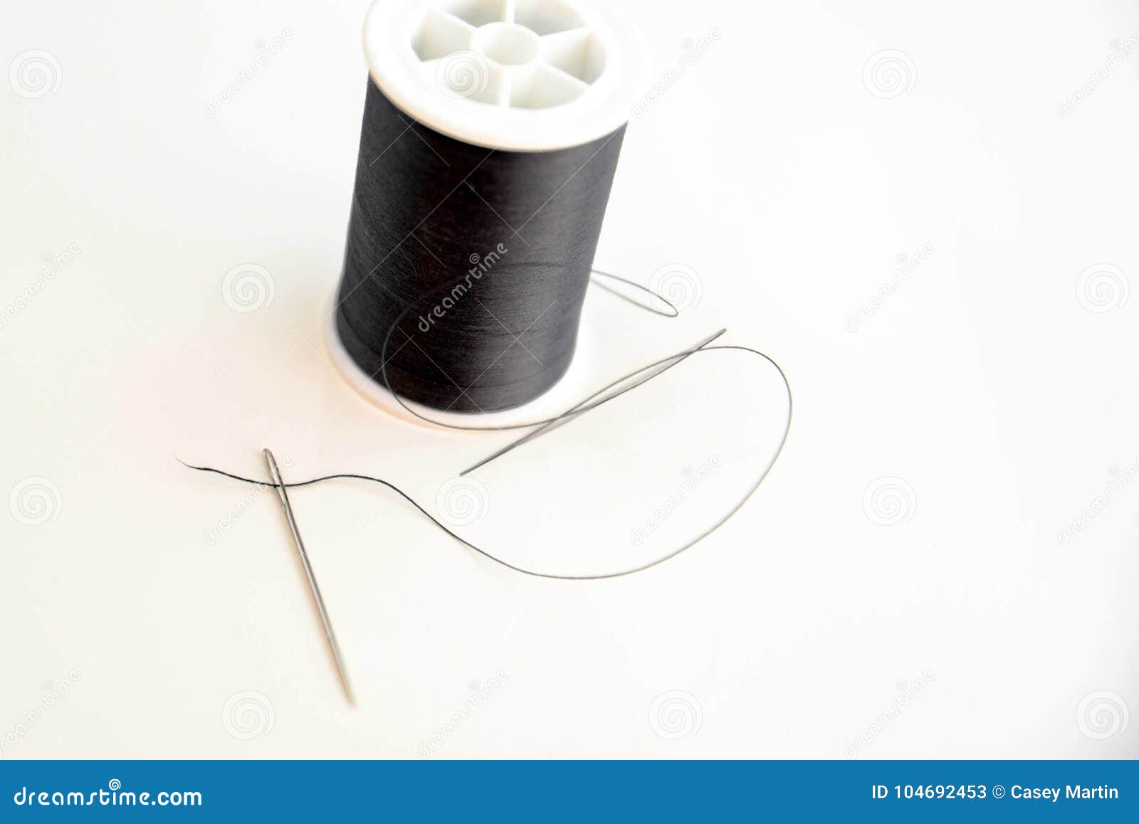 Threaded Needle and Black Spool of Thread Stock Image - Image of black ...