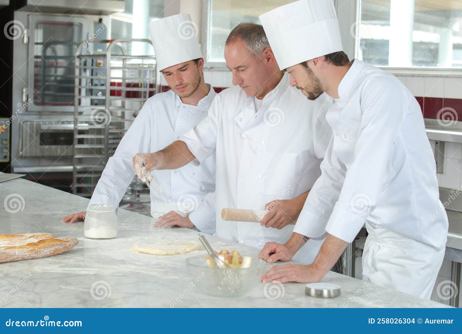 Three Bakers Wearing Work Coats and Baking Stock Photo - Image of ...