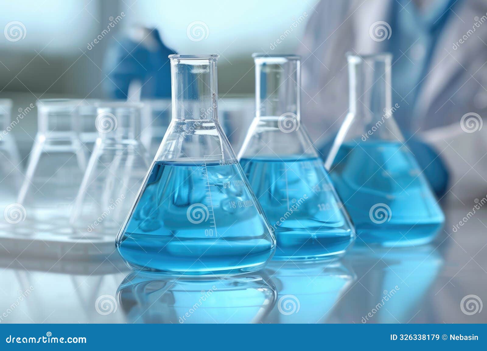 Three Beakers Filled with a Bright Blue Liquid Sit on a Table in a ...