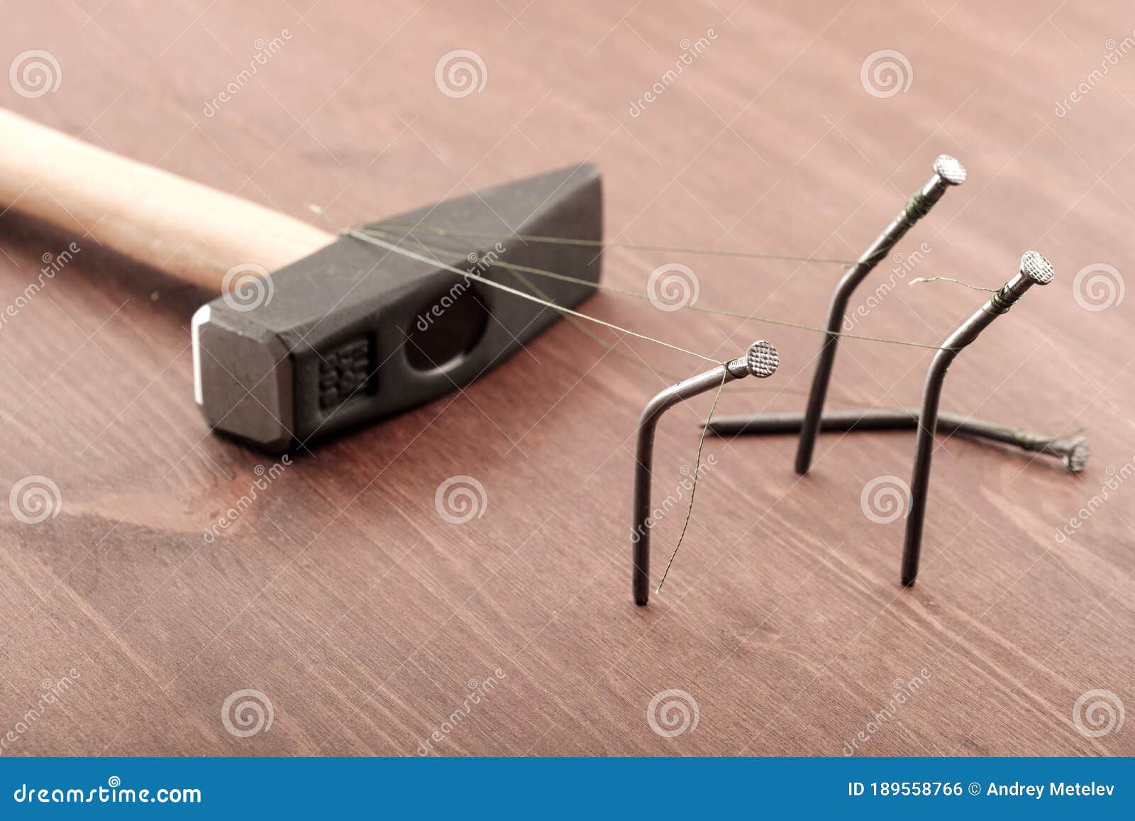 Three Bent Nails, As it Were, Pulling a Large Hammer Tied with a Rope ...