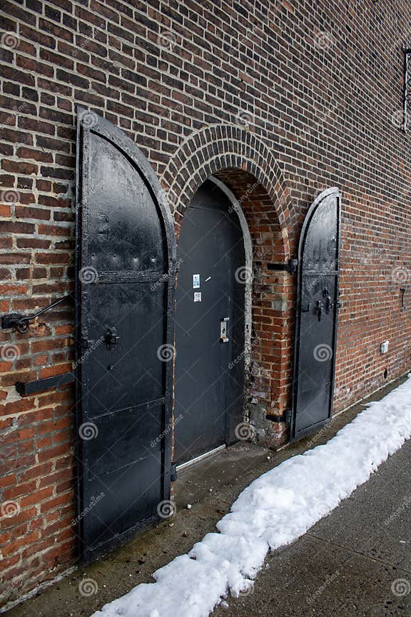 Three Black Doors are Located in the Middle of a Brick Building ...