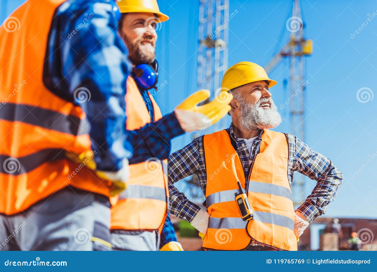 Three Builders in Reflective Vests and Hardhats Discussing Work Stock ...