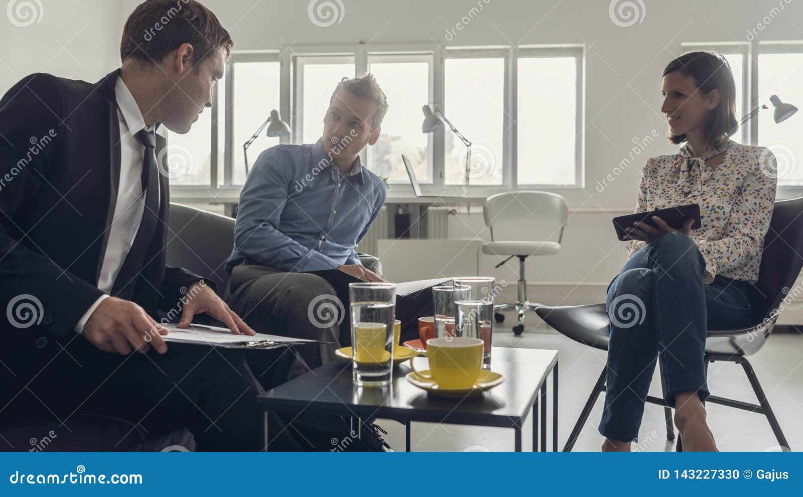 Three Business People Sitting Around a Coffee Table Stock Photo - Image ...