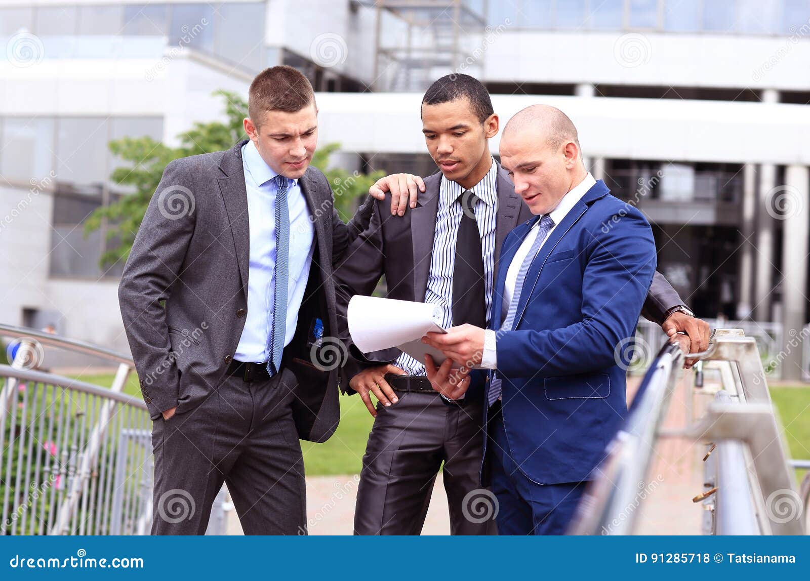 Three Businessmen Discussing Document Outside Office Stock Photo ...