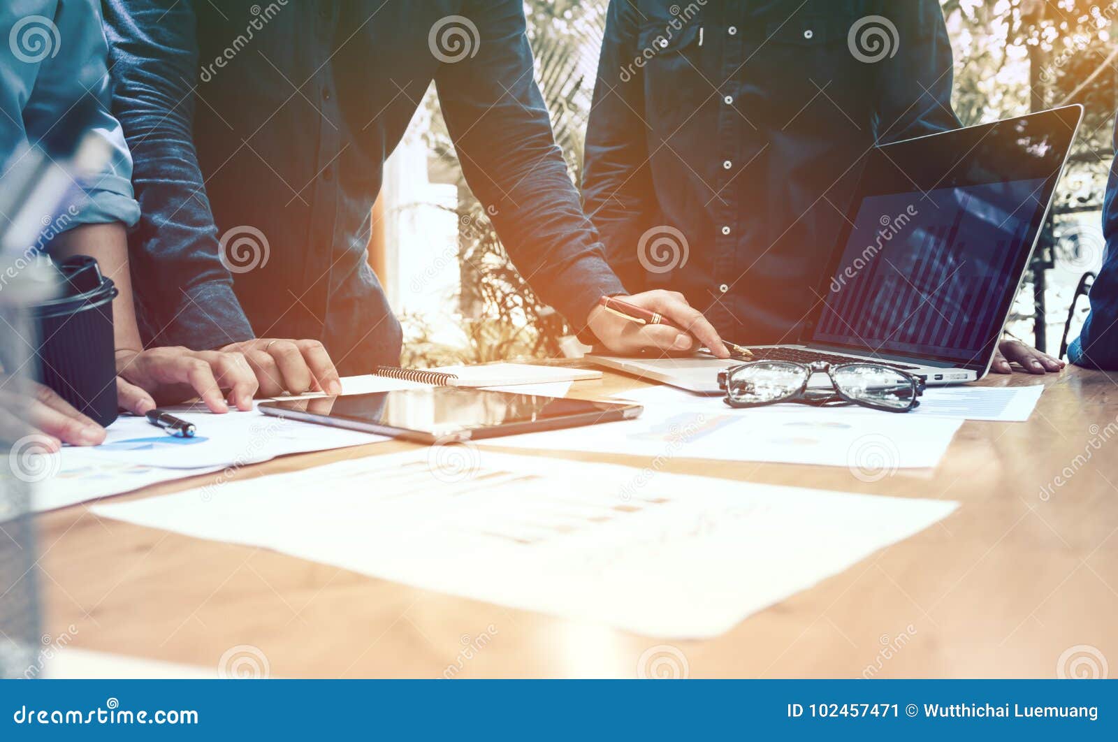 Three Businessmen Working on Laptop Computer with Documents and Stock ...