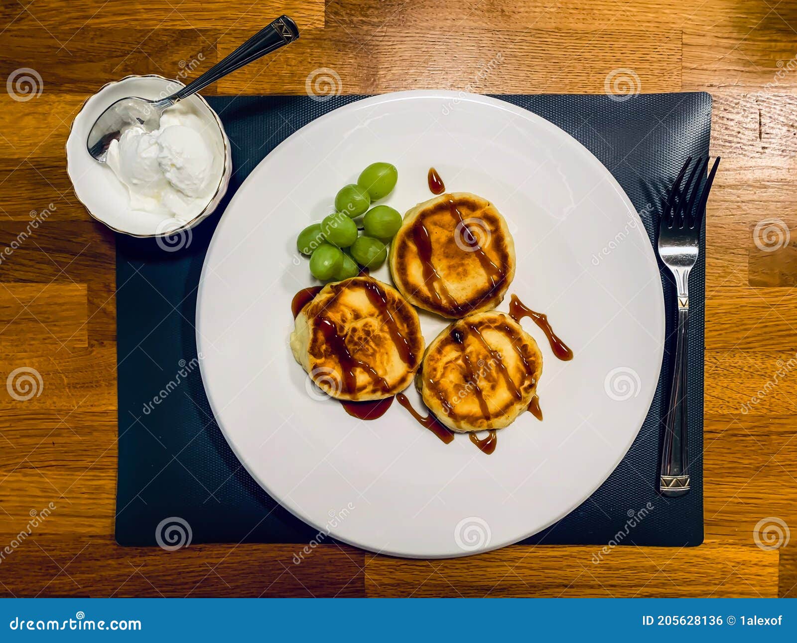 Three Cheesecakes with Maple Syrup and a Bunch of Grapes on a White ...