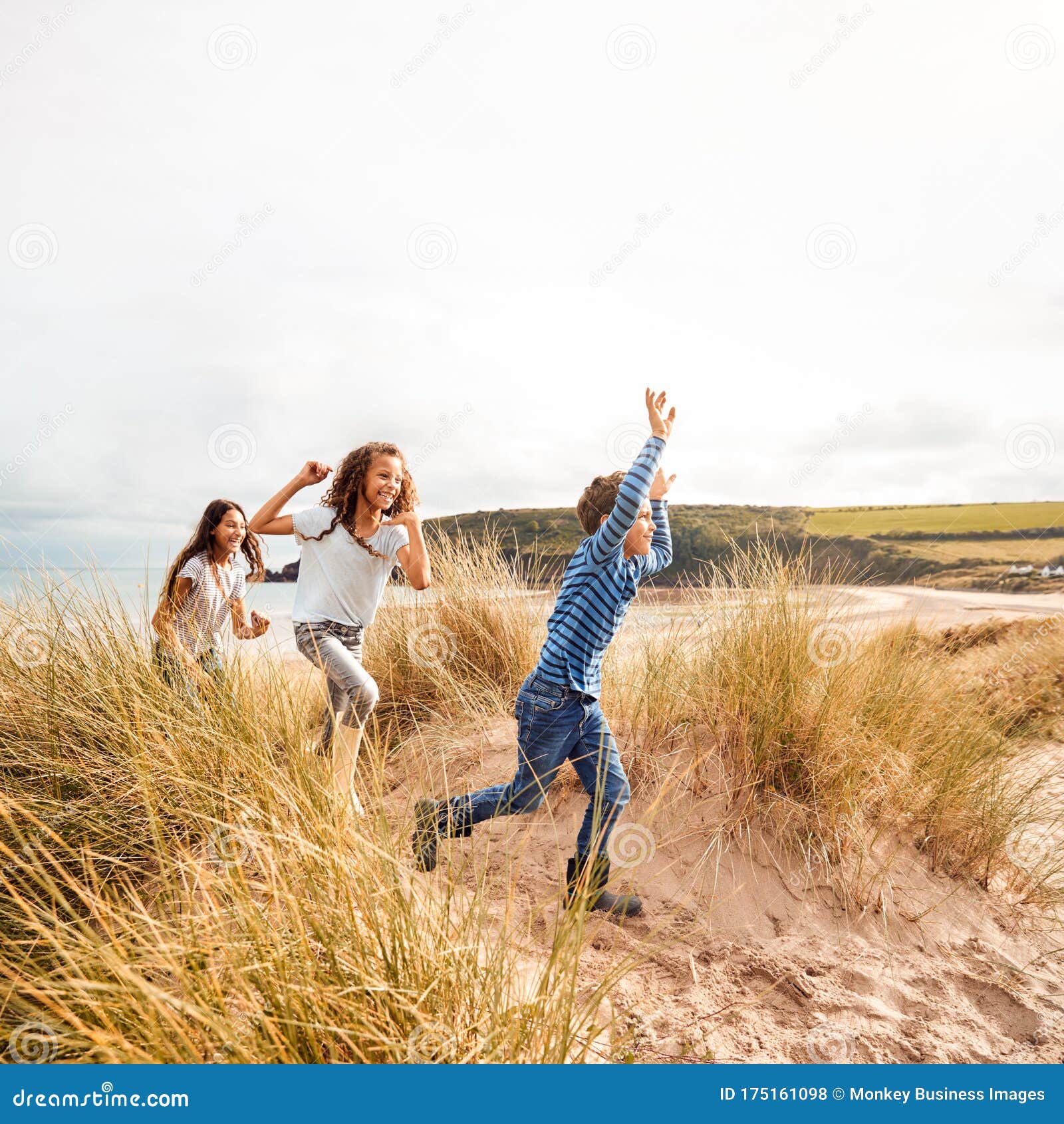 Three Children Having Fun Exploring in Sand Dunes on Winter Beach ...