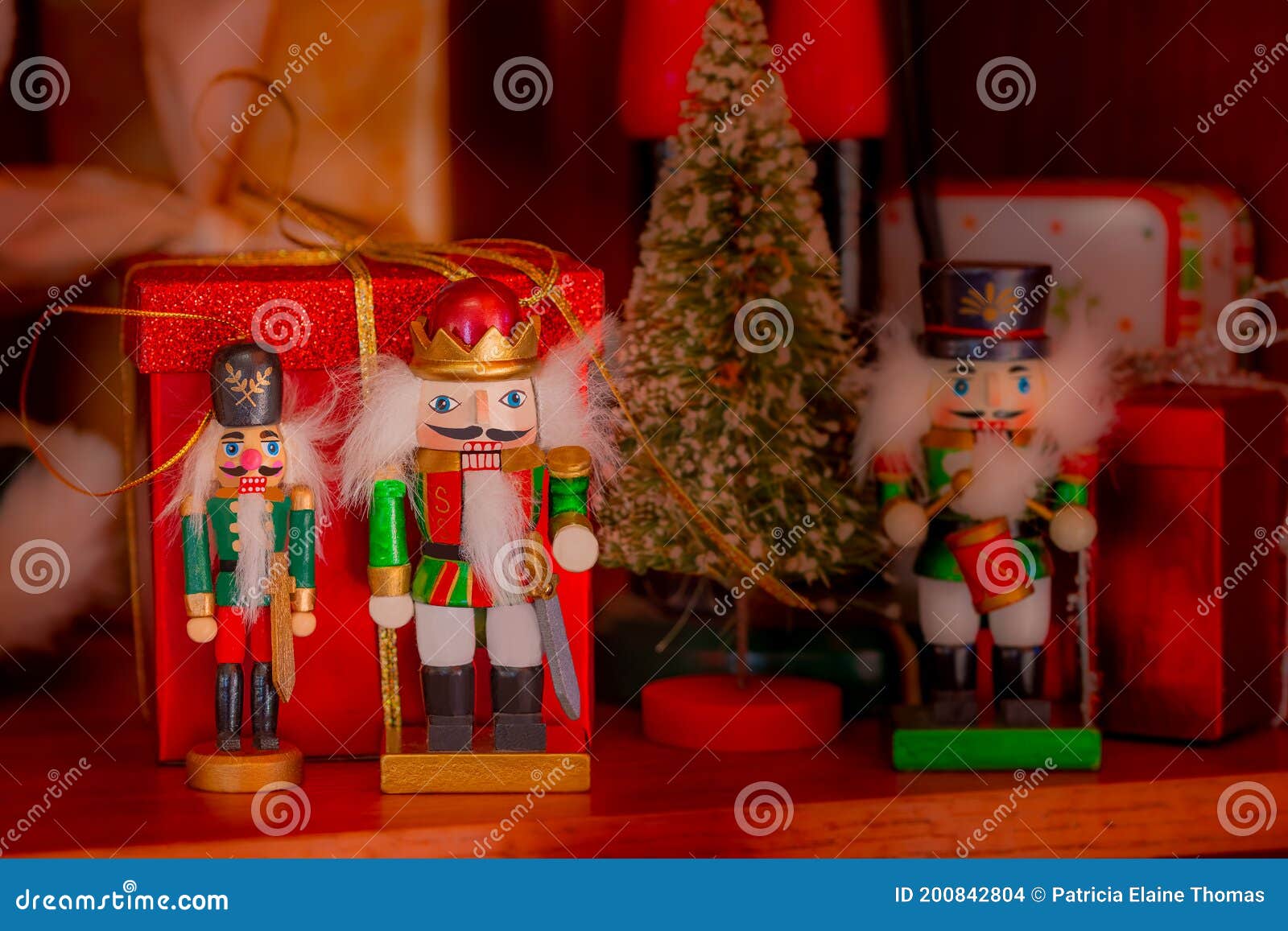 Three Christmas Nutcrackers Stand on a Shelf Next To Tree and Presents ...