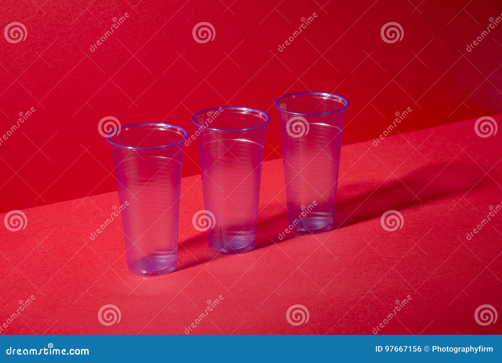 Three Clear Plastic Cups on Red Background with Copy Space Stock Photo ...