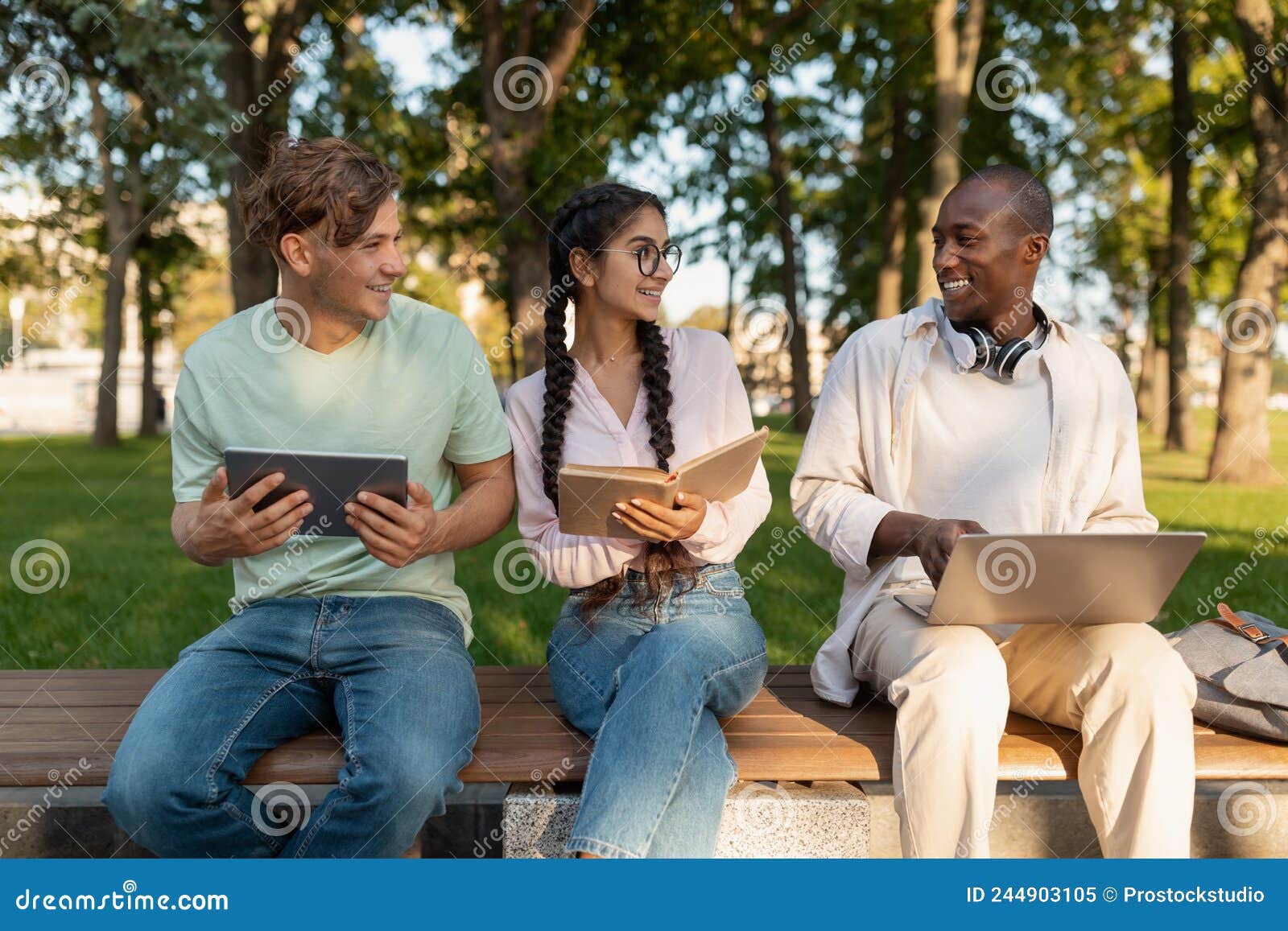 Three College Students Standing In Corridor And Using Tablet And ...