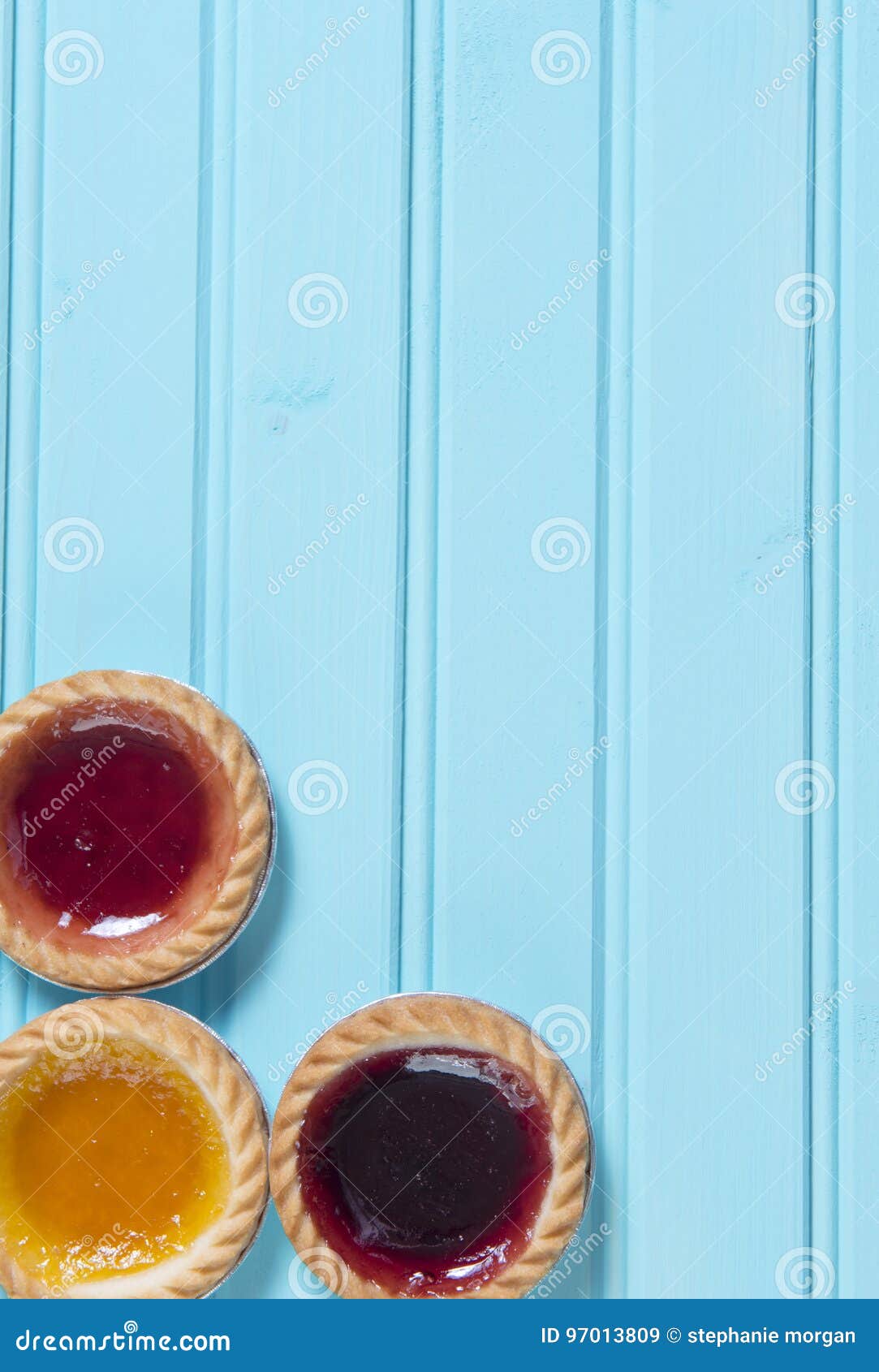Three Colourful Jam Tarts on a Blue Background Stock Image - Image of ...