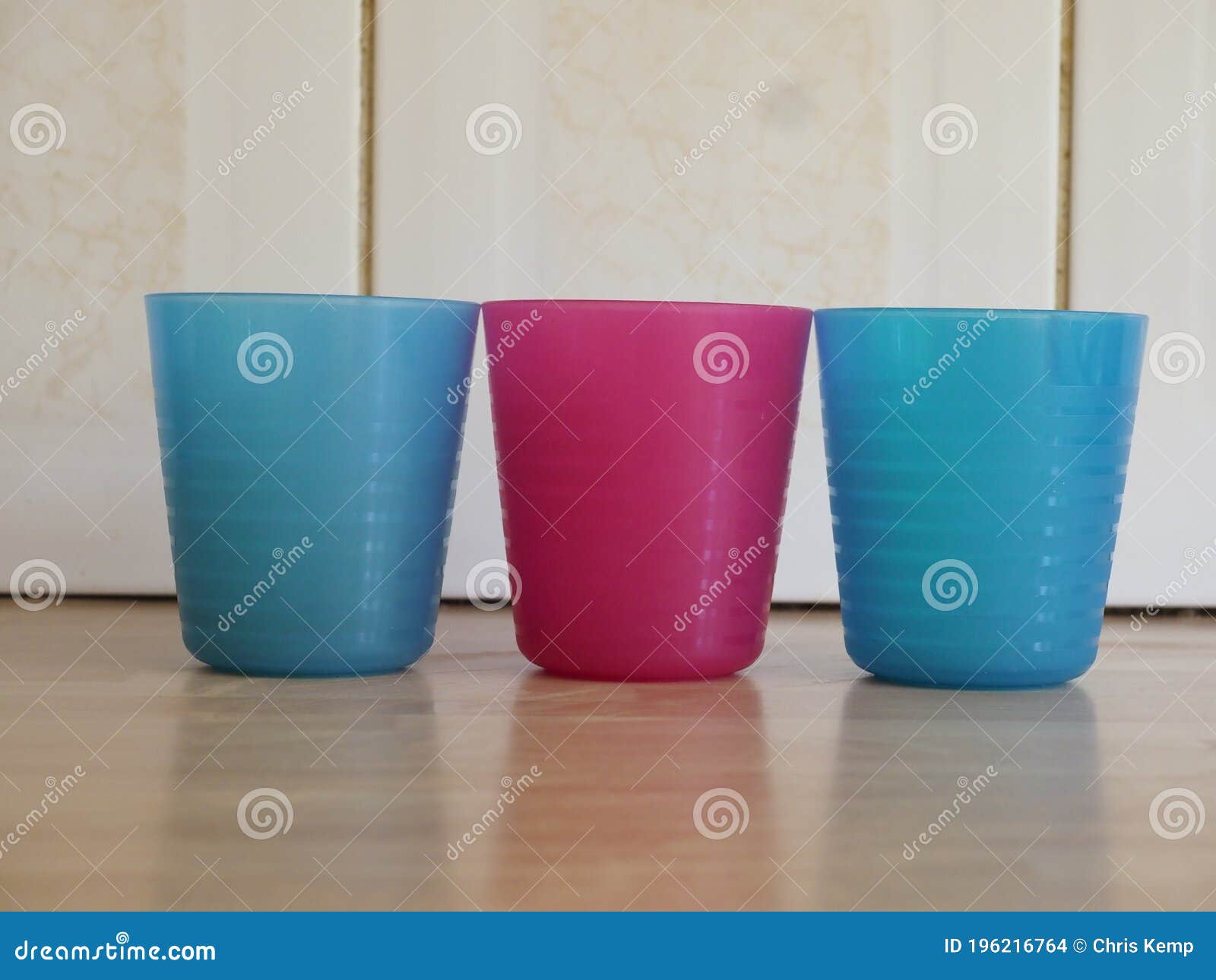 Three Colourful Plastic Beakers on a Wooden Kitchen Worktop Stock Photo ...