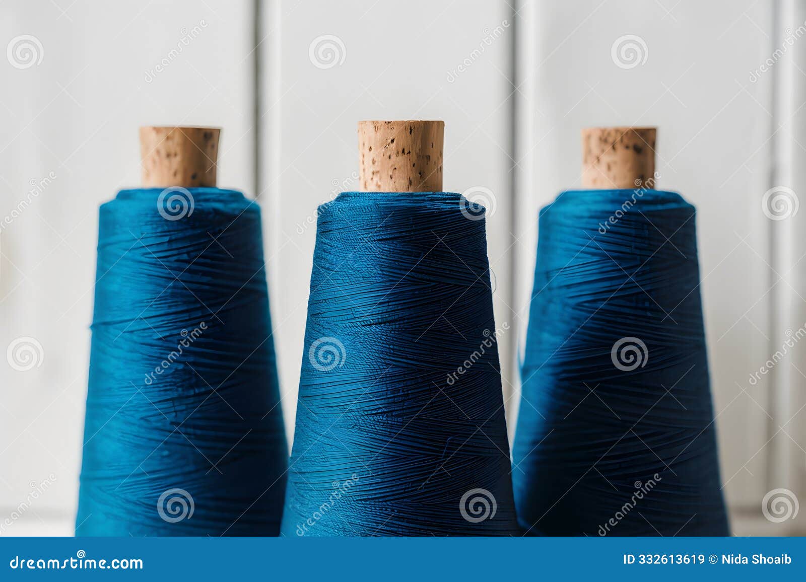 Three Conical Blue Spools of Thread on White Background with Wooden ...